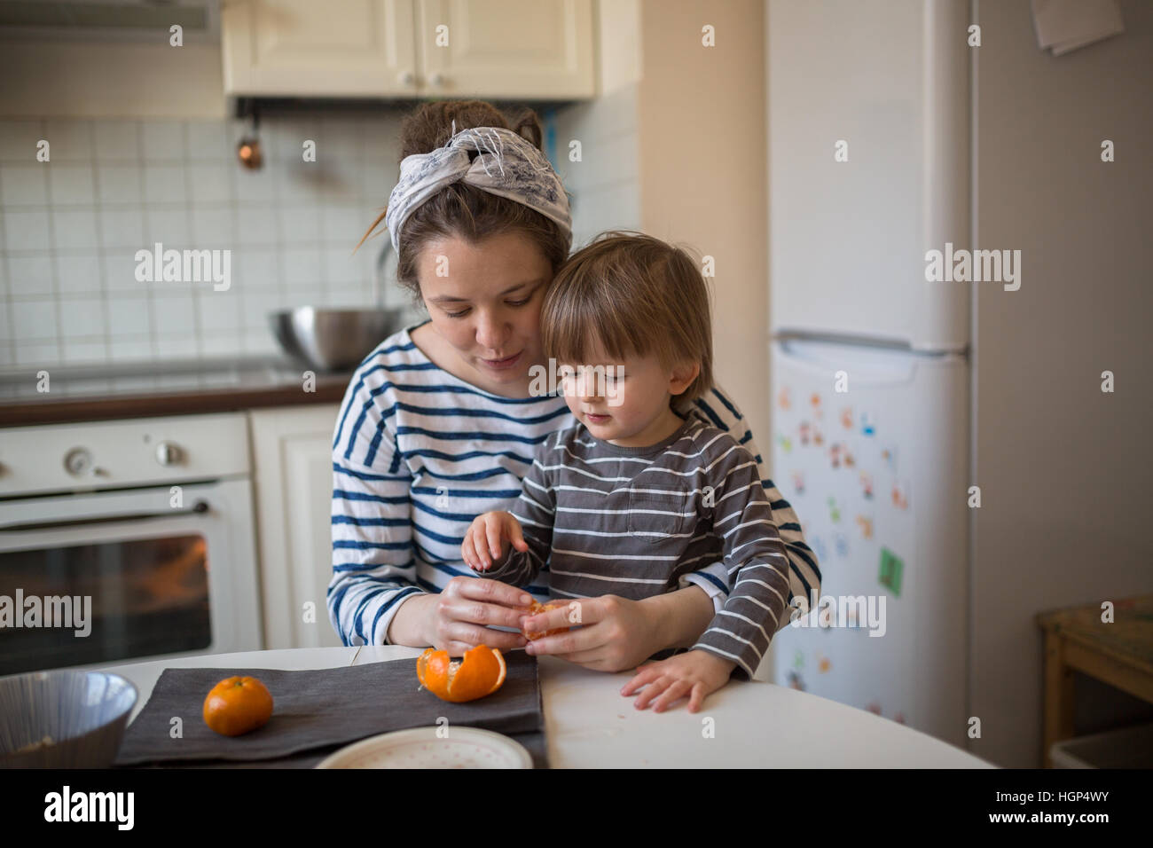 happy mother and son Toddler at the kitchen table eating tangerines ...