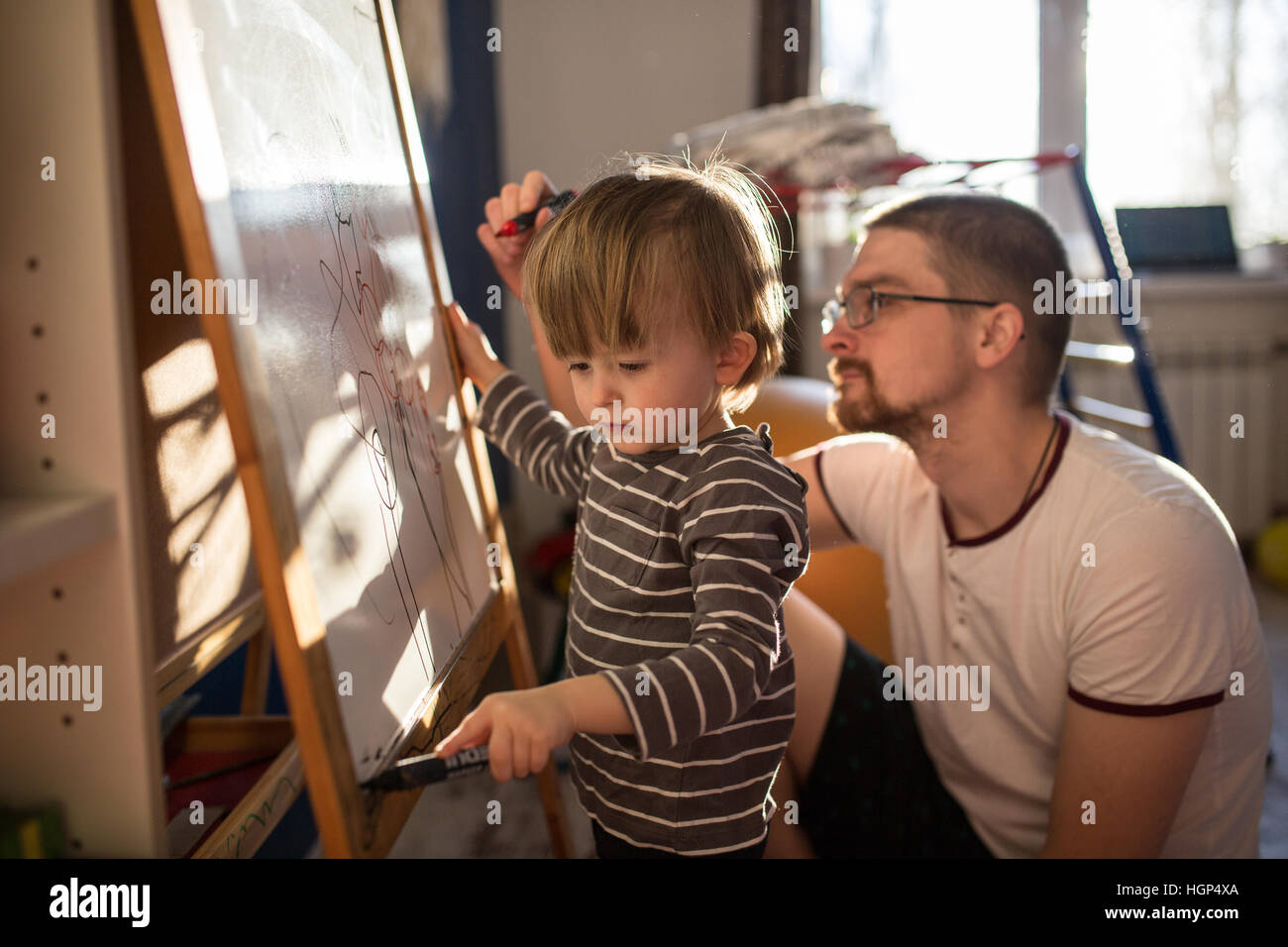 Dad and son together paint on Easel. Real interior, toning soft focus ...