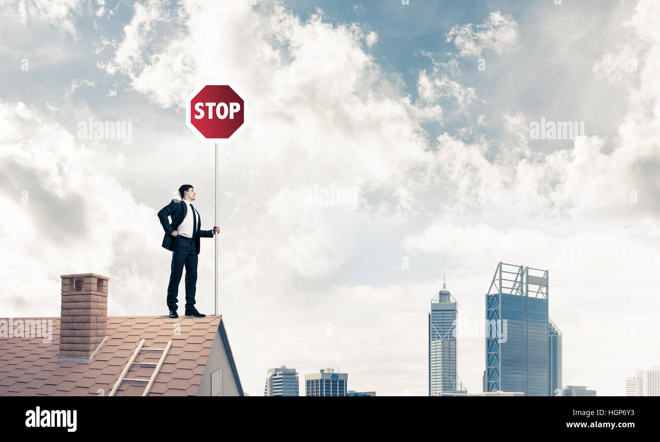 Caucasian businessman on brick house roof showing stop road sign Stock ...