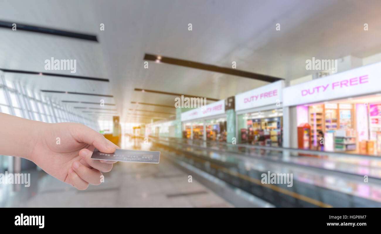 female hand holding a credit card with Blur Background of duty free ...