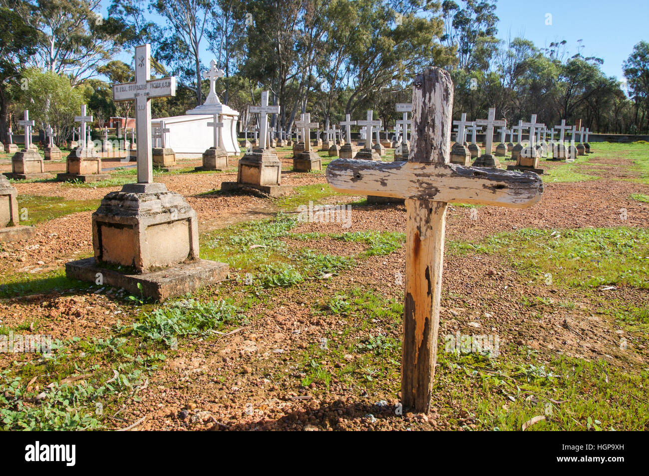 Weathered cross, with rows of headstones and cross markers with large ...