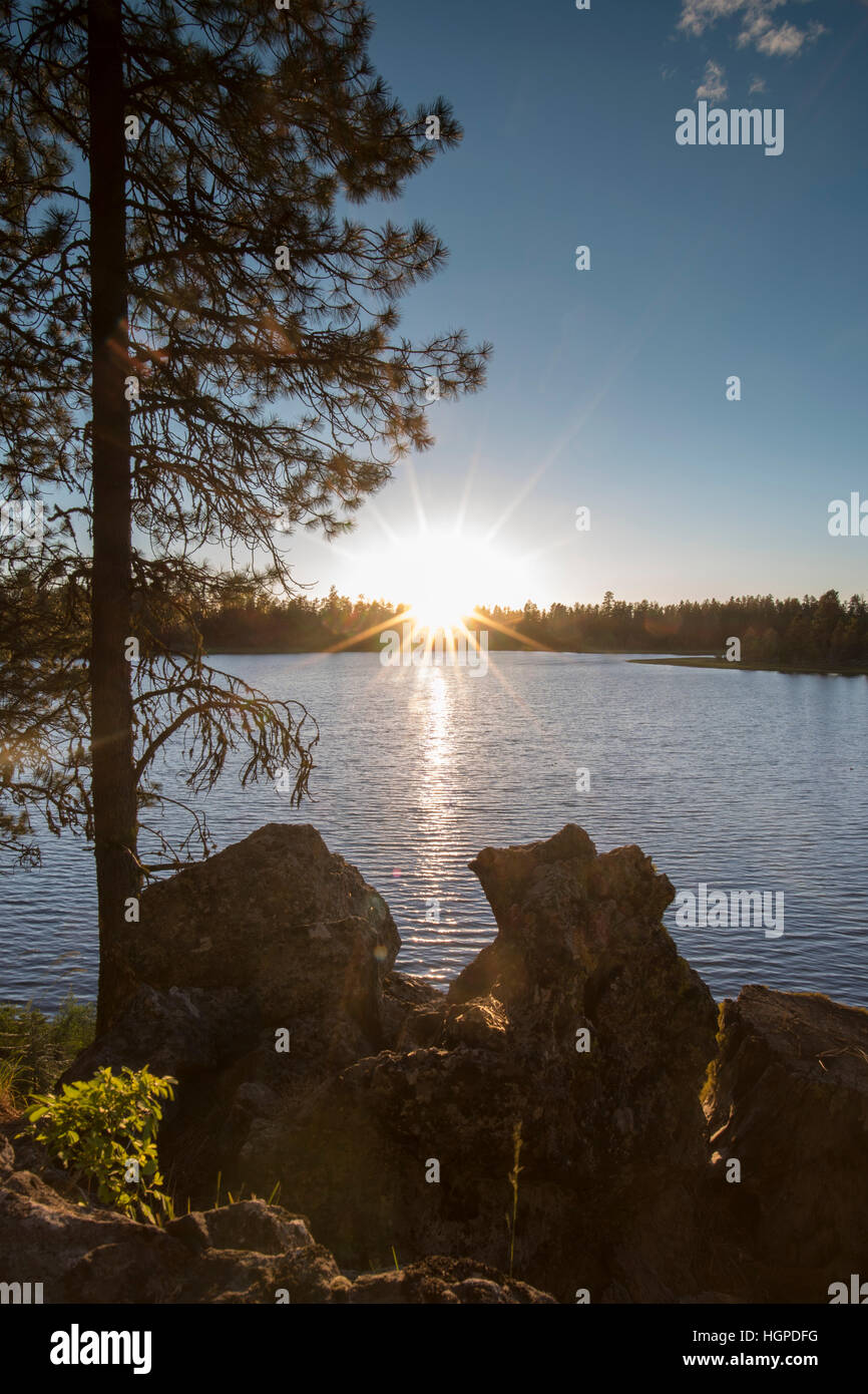 Sunset with sun star and reflection at Delintment Lake, with forest ...