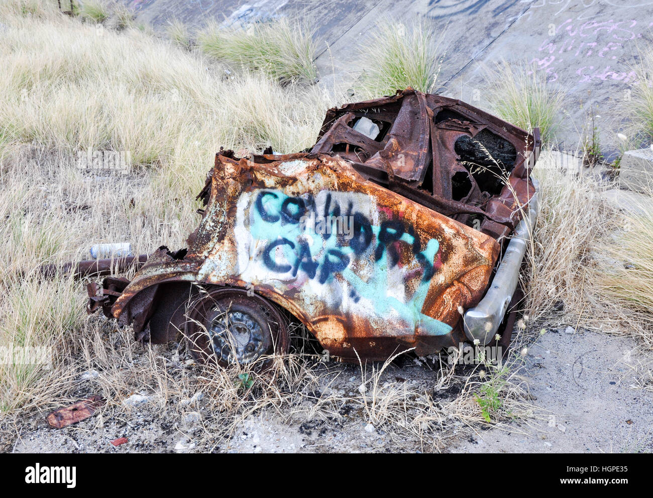 Abandoned rusted parts of a car chassis with graffiti in outdoor area ...