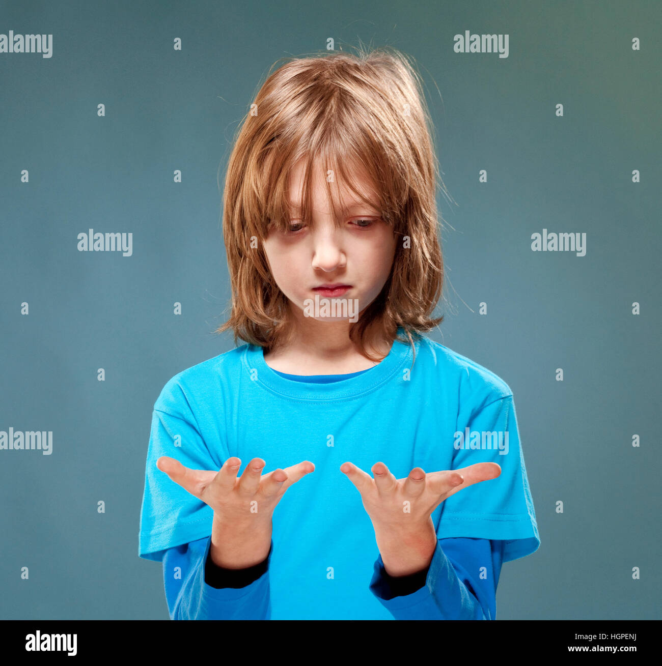 Boy in Blue Top Looking at his Hands Stock Photo - Alamy