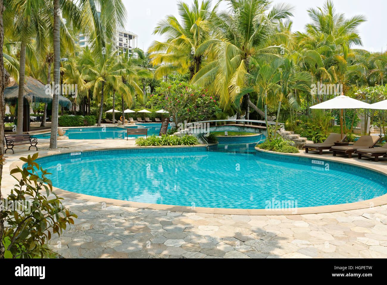 Hotel swimming pool in garden of tropical trees Stock Photo - Alamy