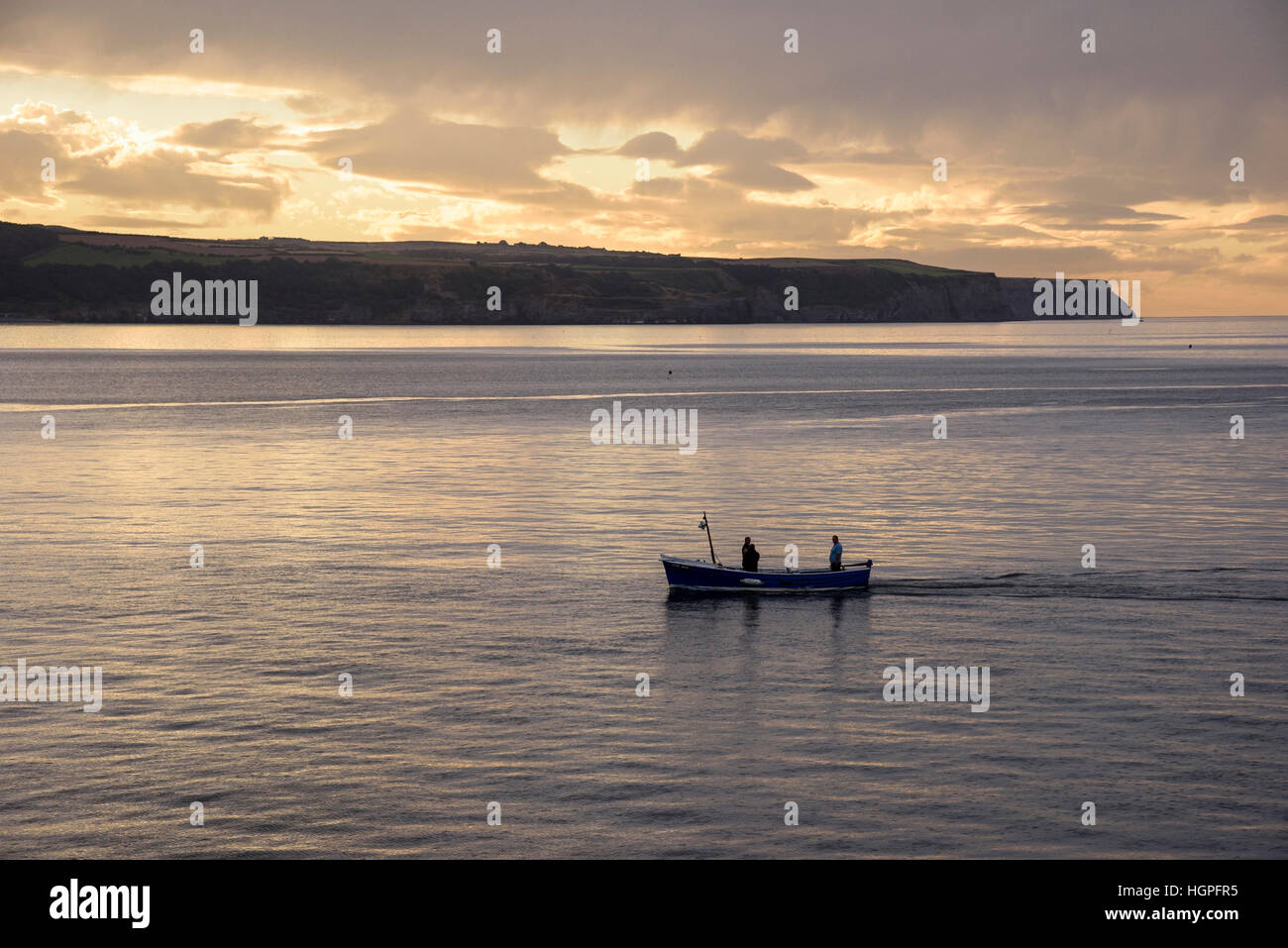 3 men, aboard a small boat, on a sea fishing trip at sunset - Whitby ...