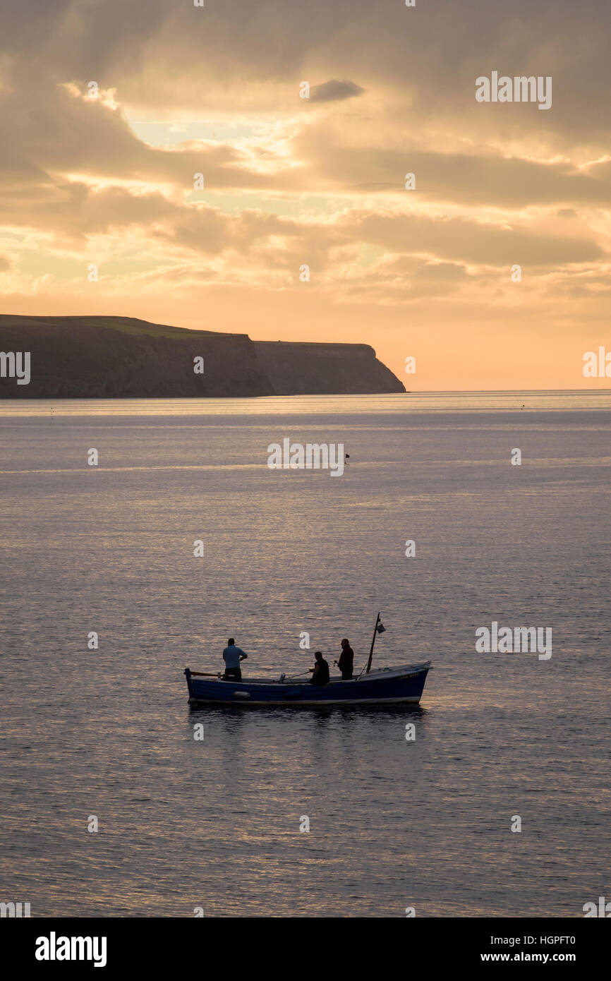 3 men, aboard a small boat, on a sea fishing trip at sunset - Whitby ...