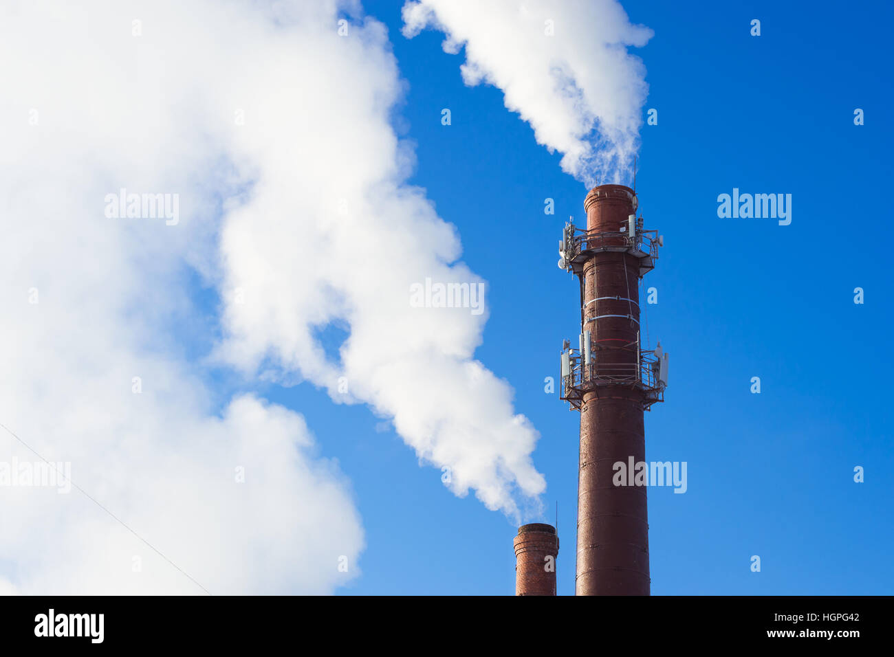 High brick chimney heating boiler house clubs up smoke on blue sky ...