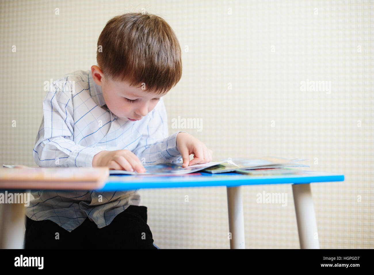 little boy is sitting at his desk and reads a book Stock Photo - Alamy