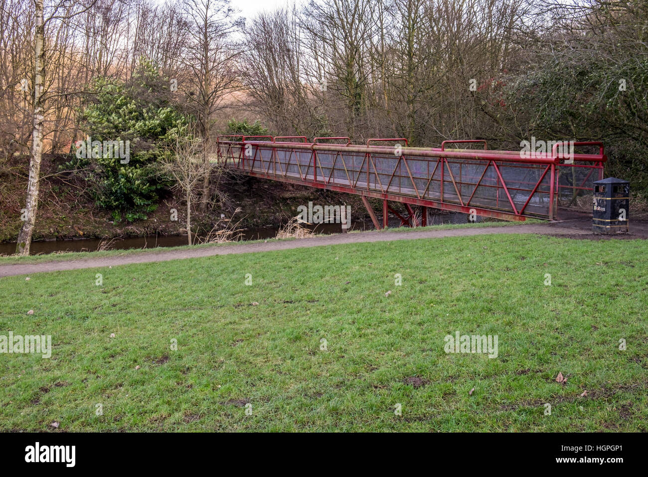 A red metallic bridge crossing a small river Stock Photo - Alamy