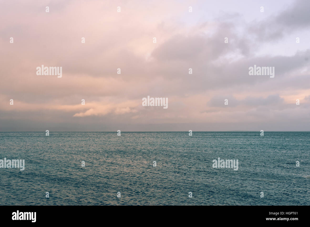 Peaceful view of open sea and empty horizon at sunset with pink clouds ...