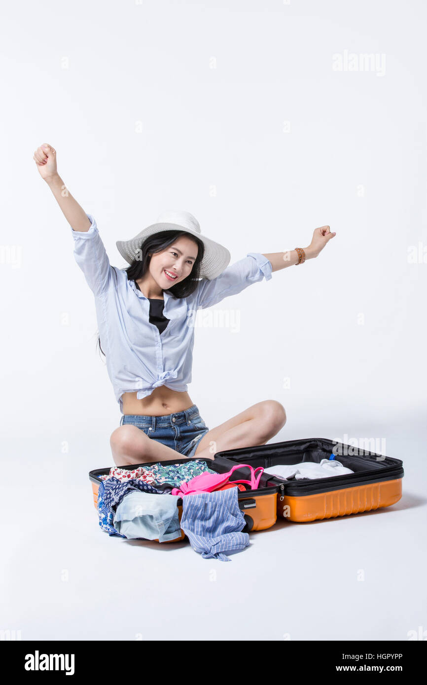 Young smiling woman in casual clothes sitting down packing carrier ...
