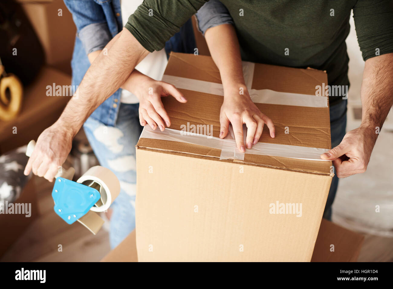 Couple packing cardboard boxes with adhesive tape Stock Photo - Alamy