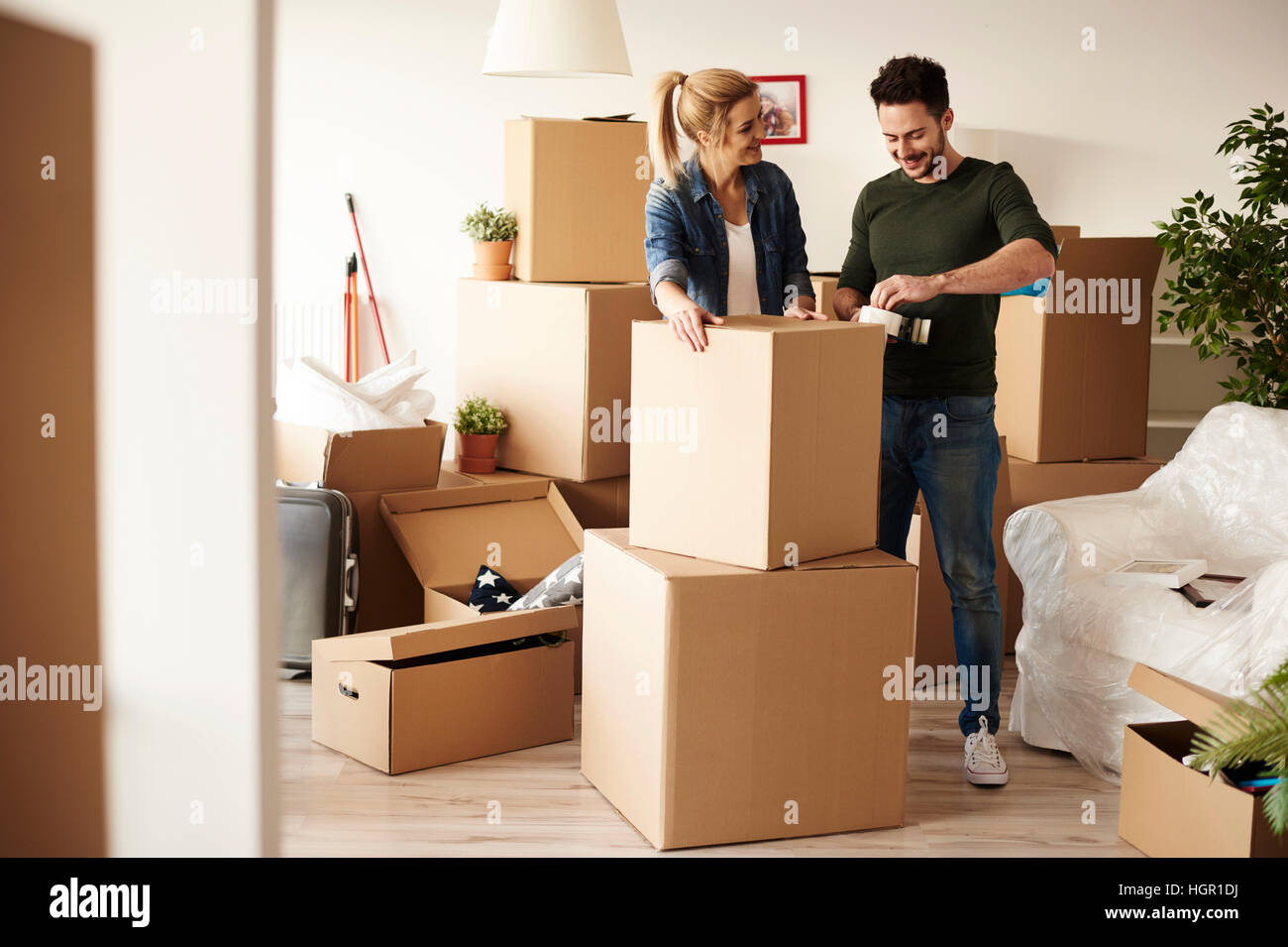 Couple packing stuff among plenty of cardboard boxes Stock Photo - Alamy