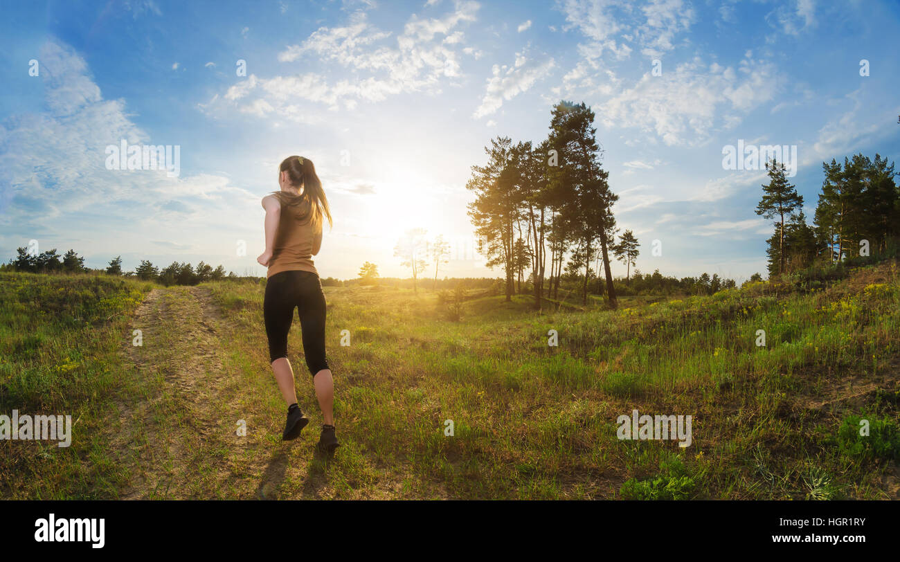 Young woman jogging outdoors. View from the back, on a background of ...