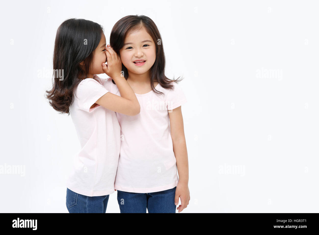 Twin girls talking in whisper Stock Photo - Alamy
