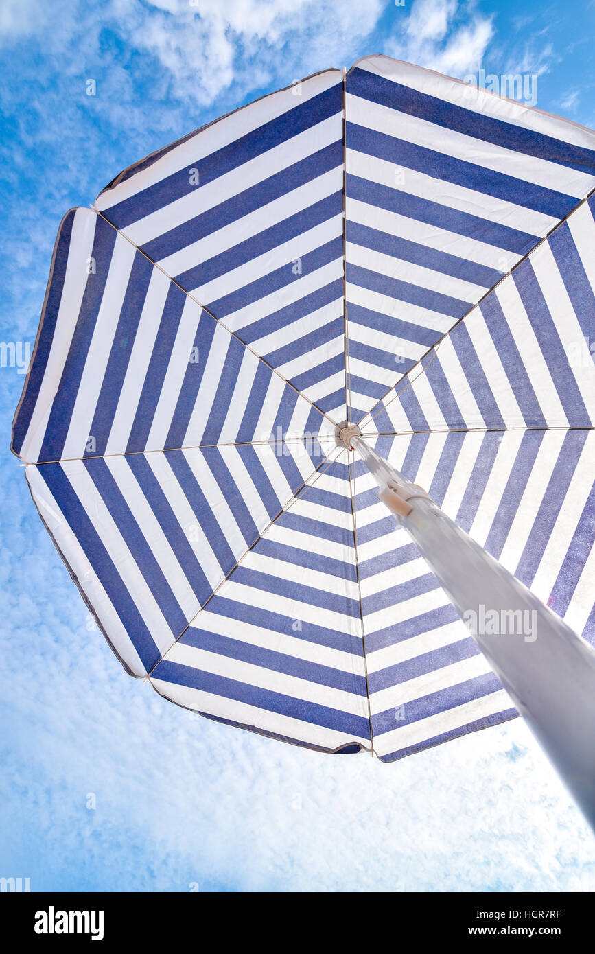 Blue and white sun protection beach umbrella and blue sky with clouds ...