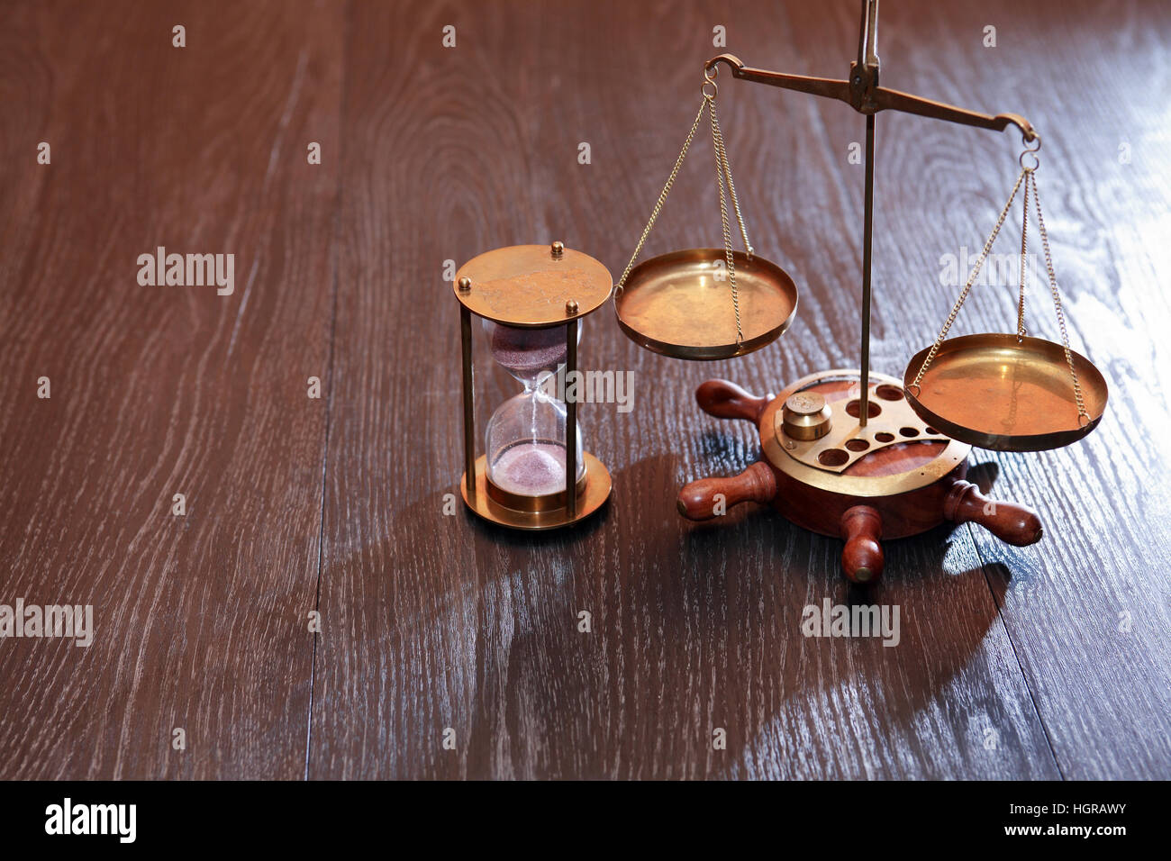 Vintage still life. Weight scale and hourglass on wooden background ...