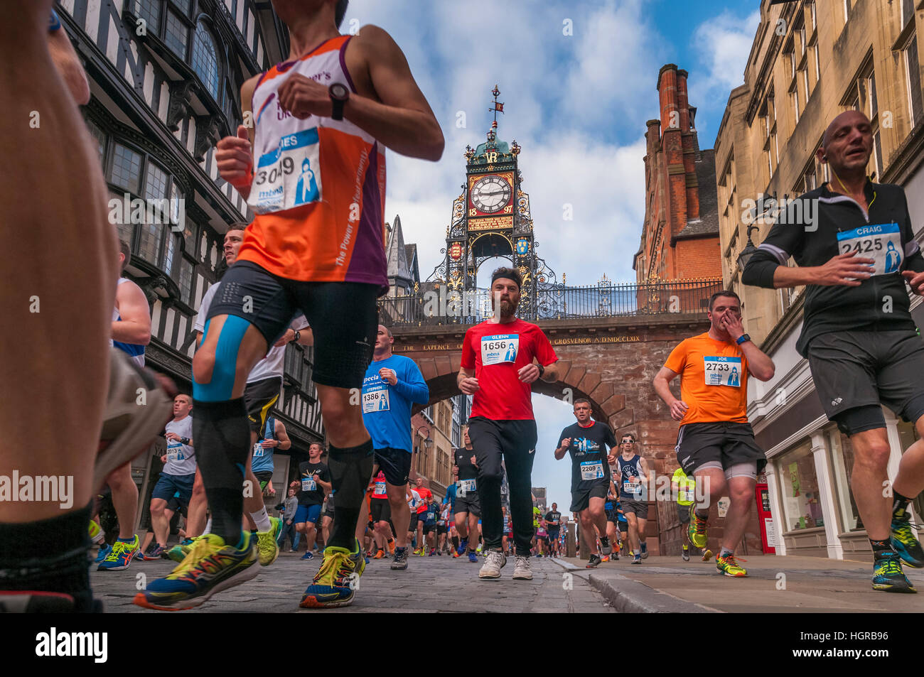 Marathon runners pass under the Eastgate clock bridge in Chester ...