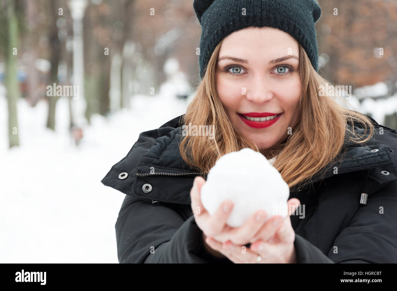 Beautiful female posing with snowball outside in park wearing black ...