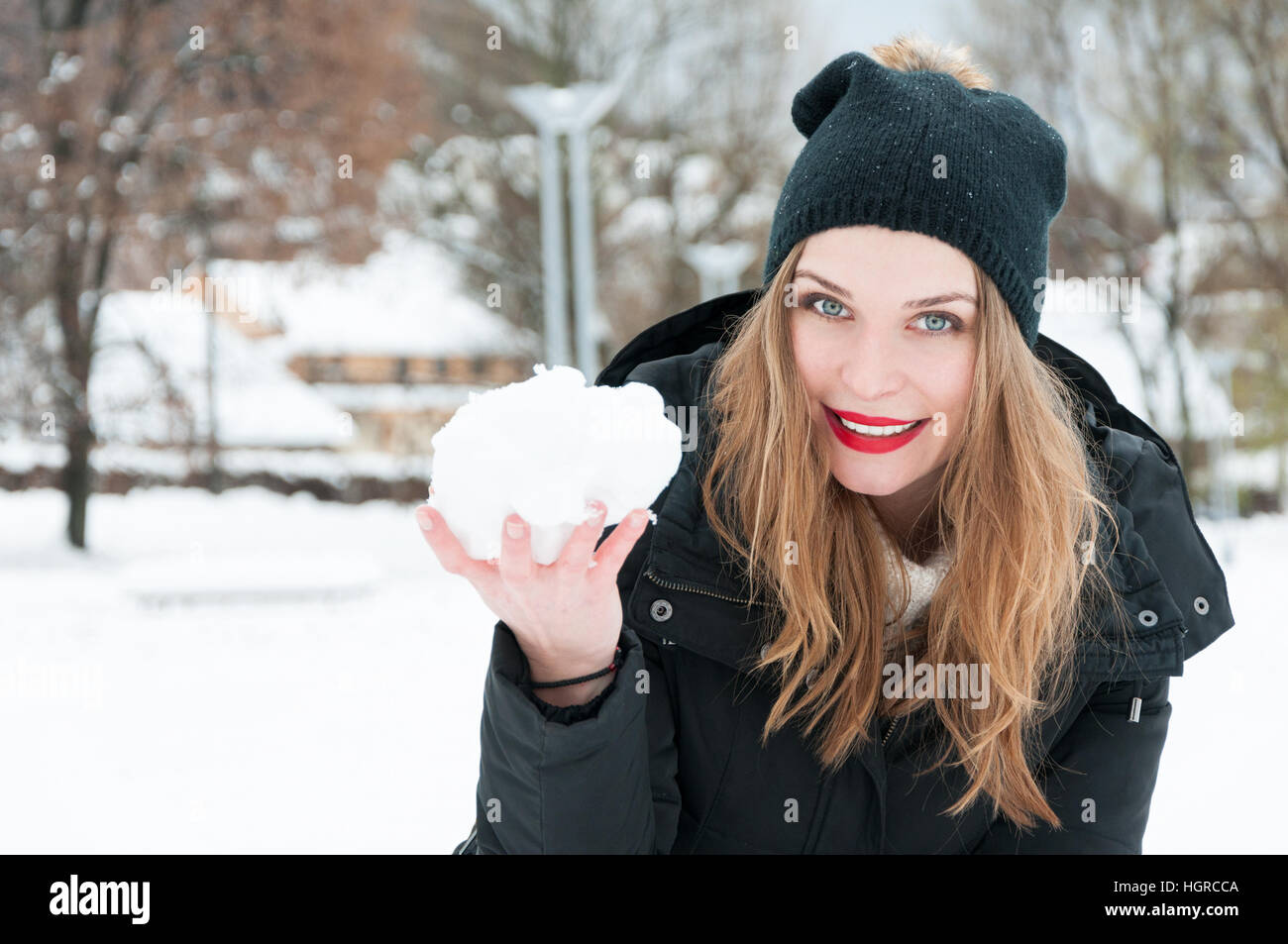 Attractive female posing holding snowball wearing hat and winter ...