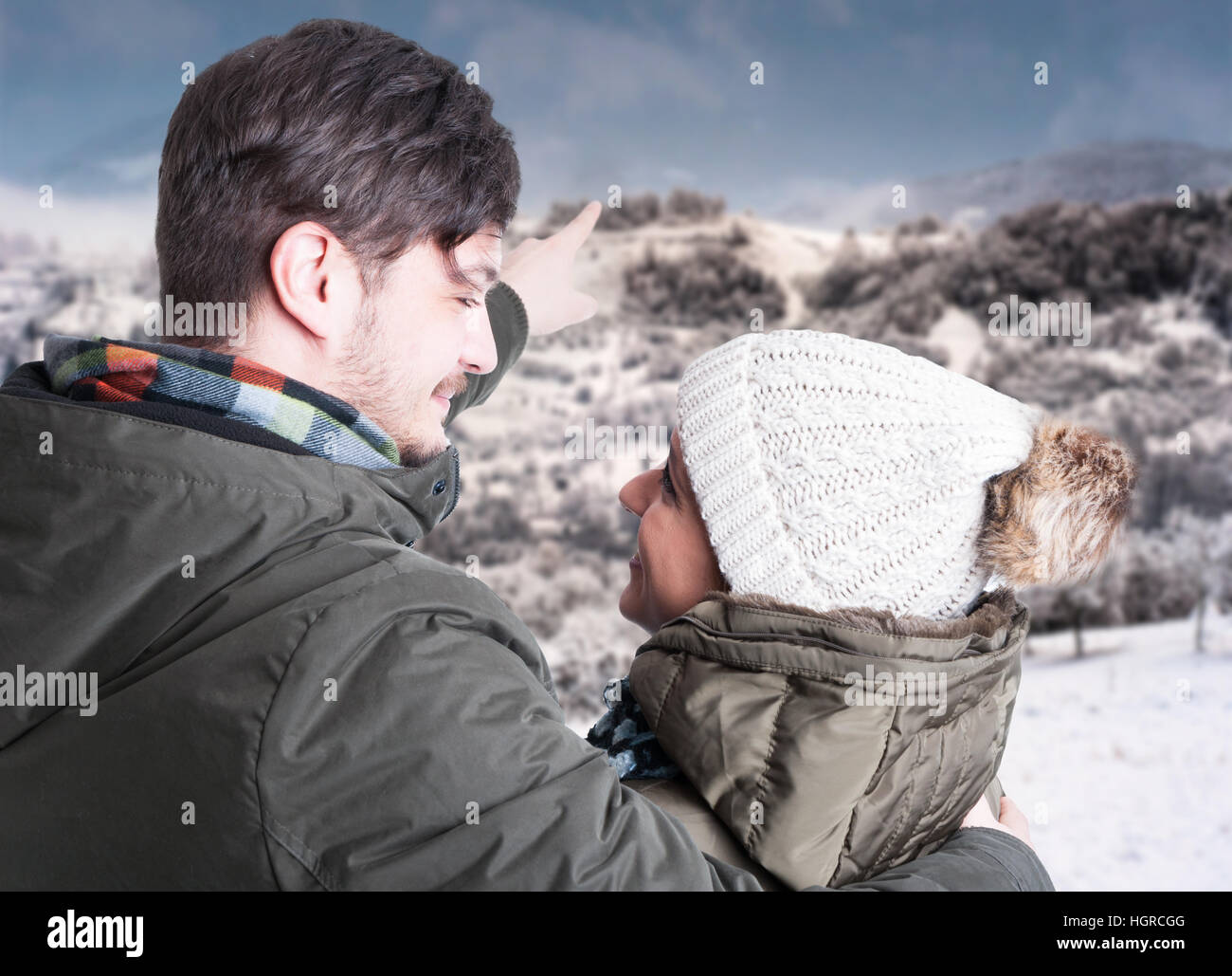 Joyful man indicate something to smiling female outdoors in snowy ...