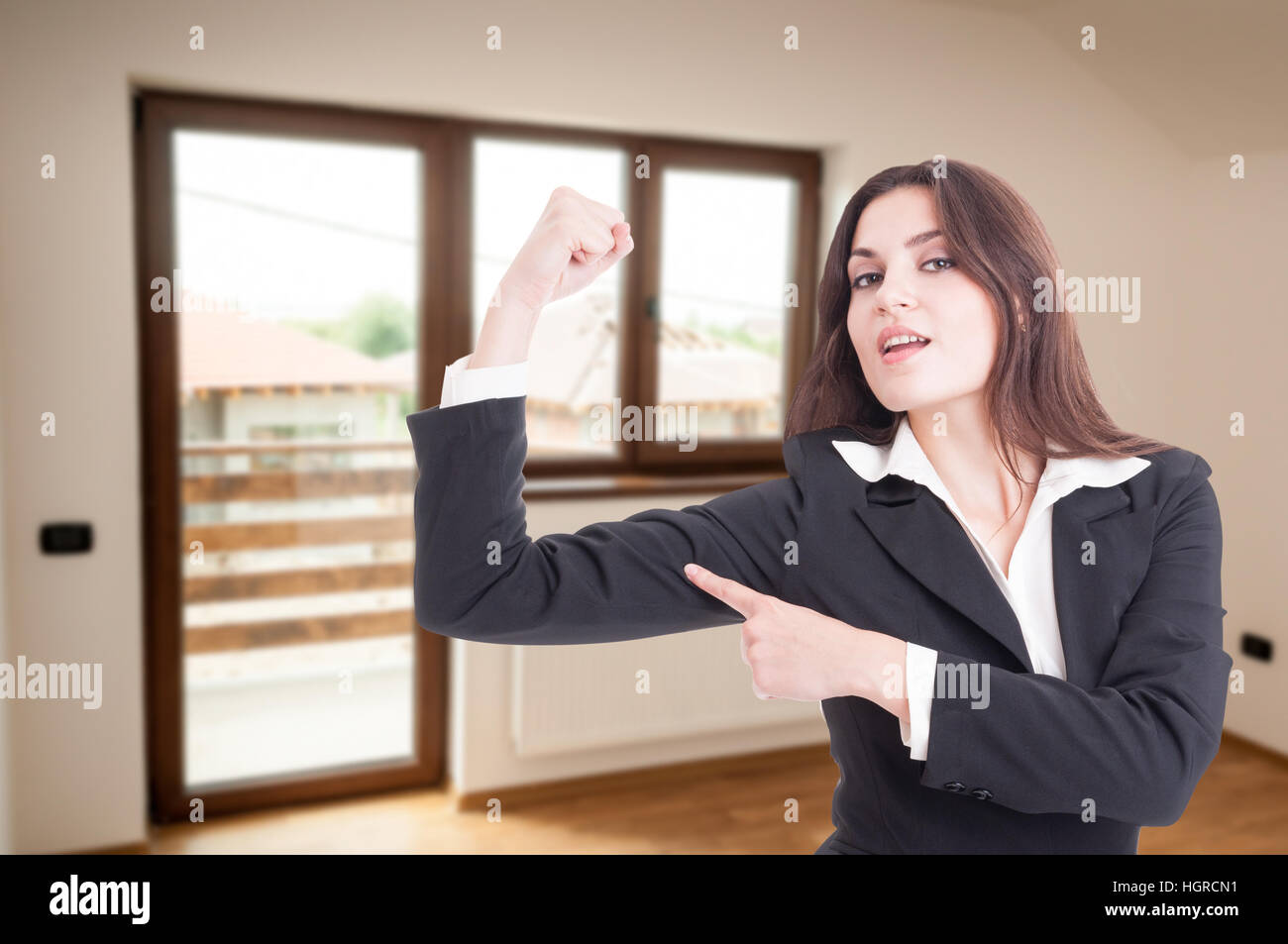 Attractive female realtor showing her muscle as strength and confidence ...