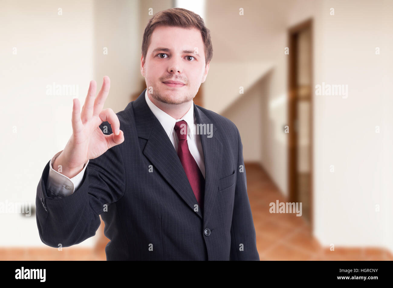 Young positive realtor showing ok sign as great rented house concept ...