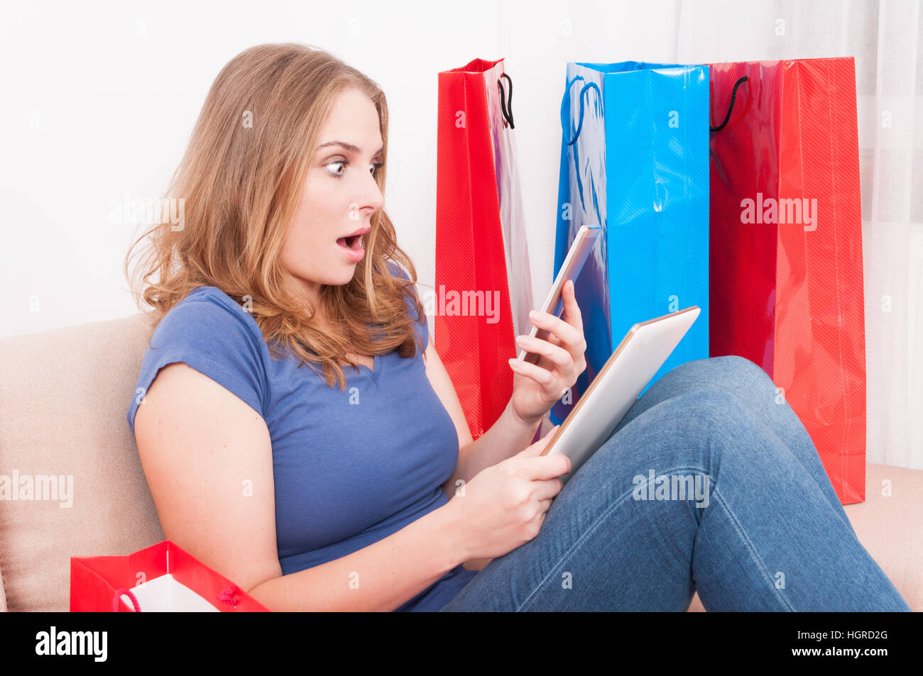 Lady being amazed holding smartphone and tablet with shopping bags ...