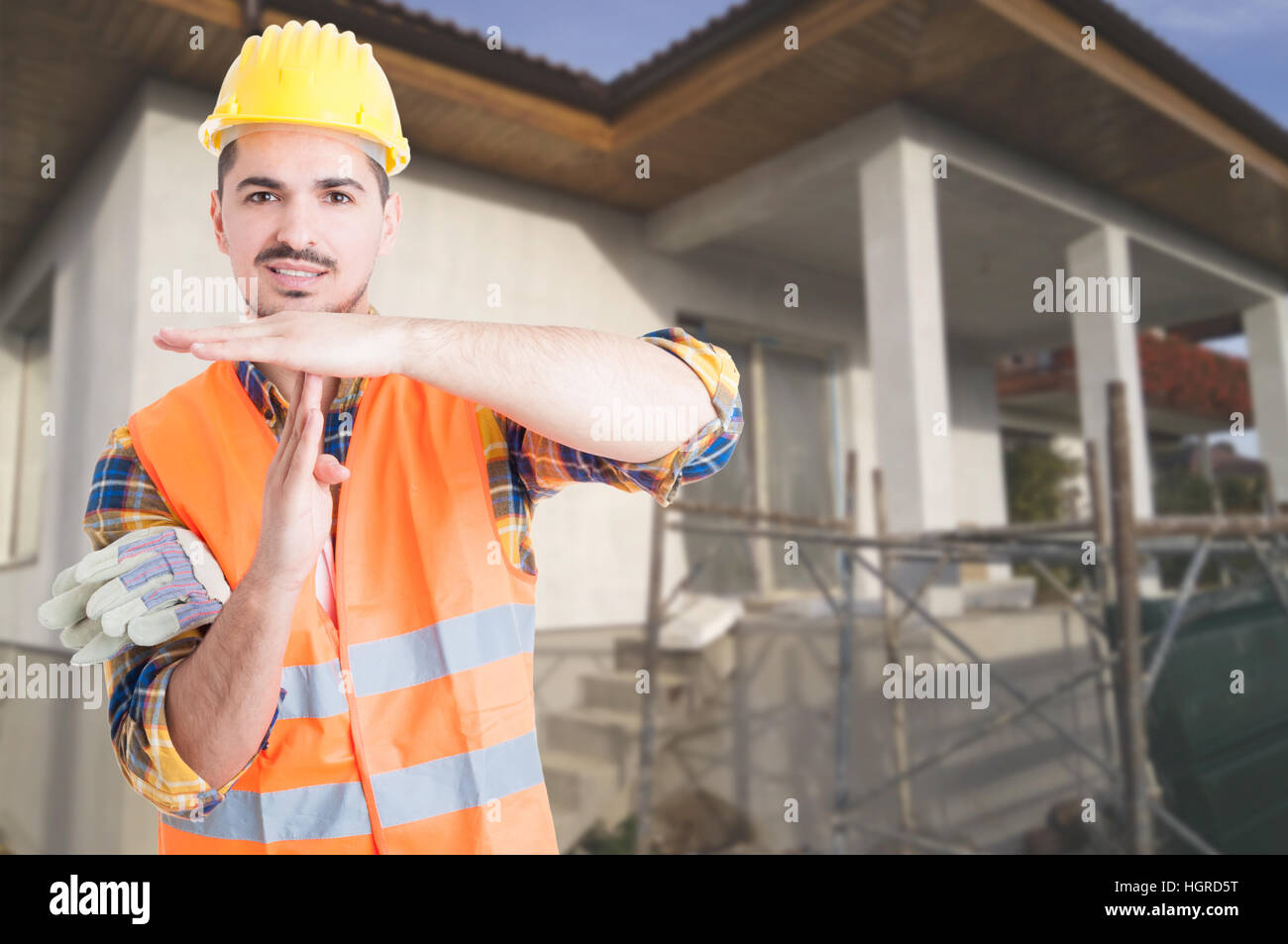 Young architect standing outside on building site and doing timeout or ...