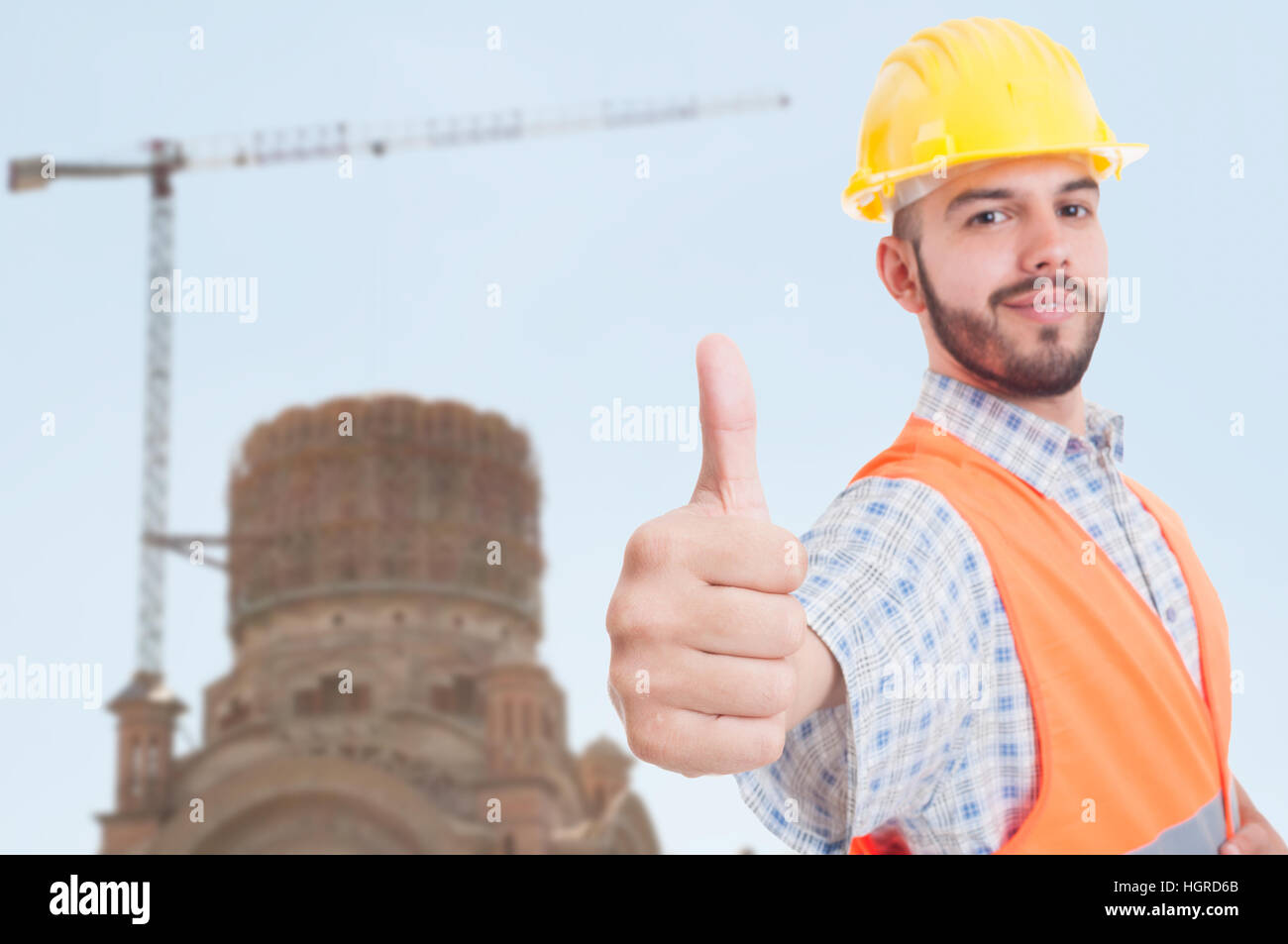 Handsome engineer showing thumb up in closeup with renovated building ...