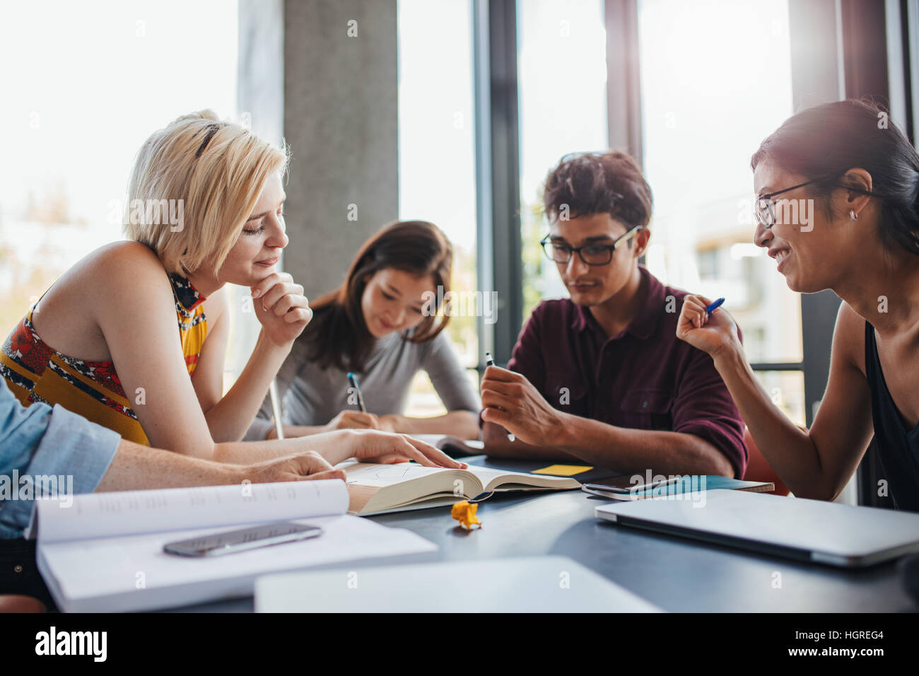 Young people sitting together at table working on school assignment ...