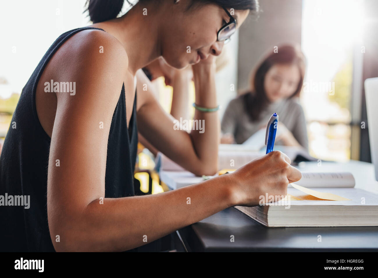Close up shot of young female students writing notes with classmates ...