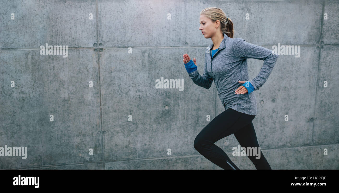 Side view shot of fit young female running outdoors. Healthy woman ...