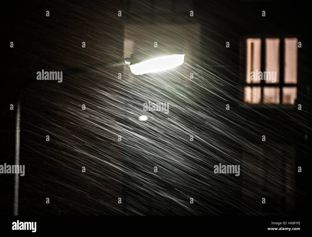 Stormy snowfall in front of a street light during the early morning in ...