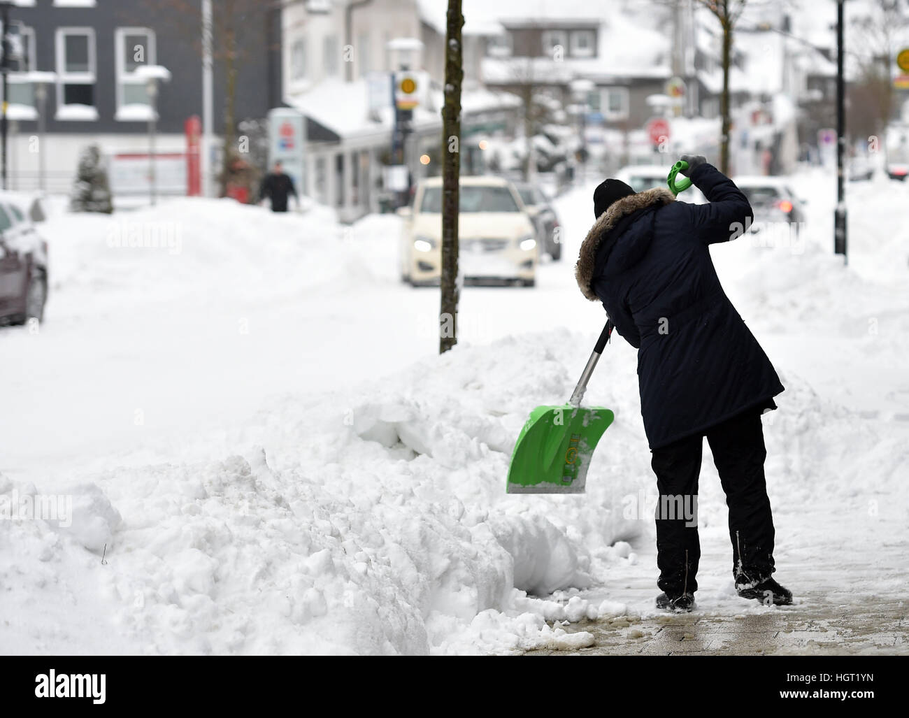 Winterberg, Germany. 13th Jan, 2017. A woman clears snow with a shovel ...