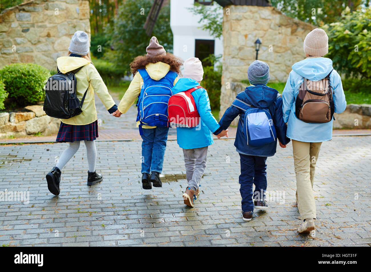 Rear view of classmates holding by hands and moving to school Stock ...