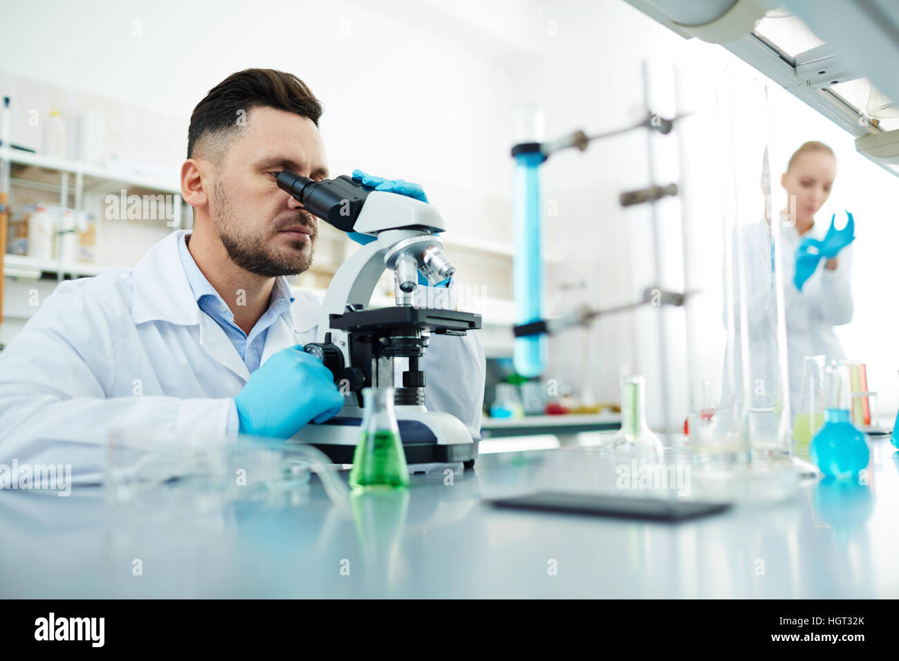 Scientist studying new elements in microscope Stock Photo - Alamy