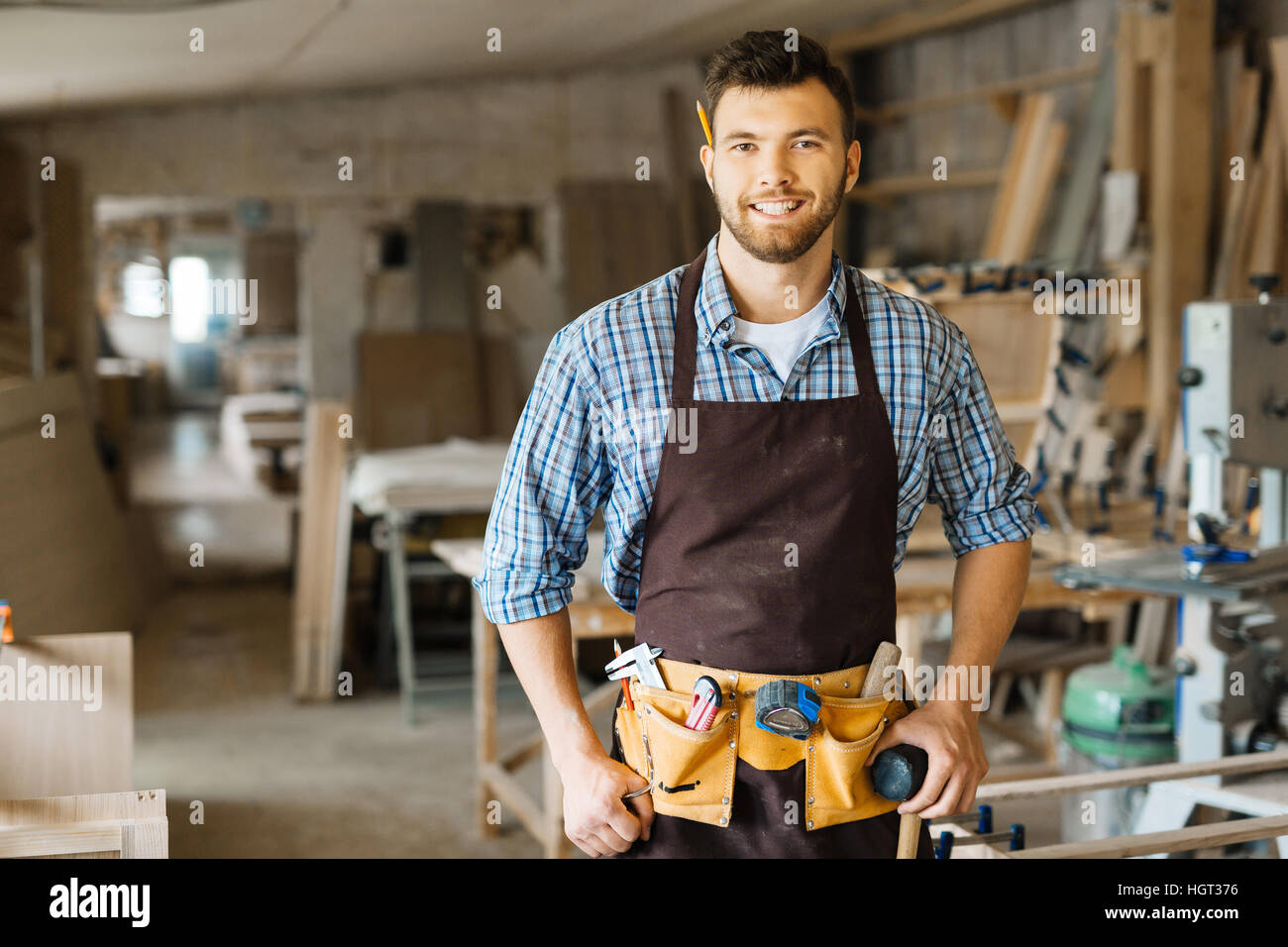 Happy young carpenter in uniform looking at camera Stock Photo - Alamy