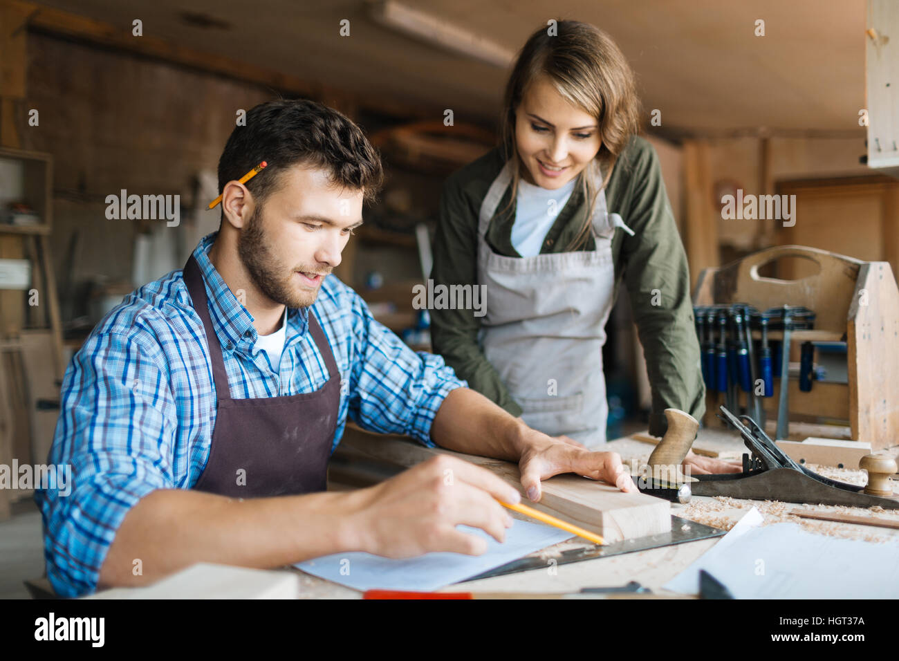 Small group of carpenters taking measures of wooden plank Stock Photo ...