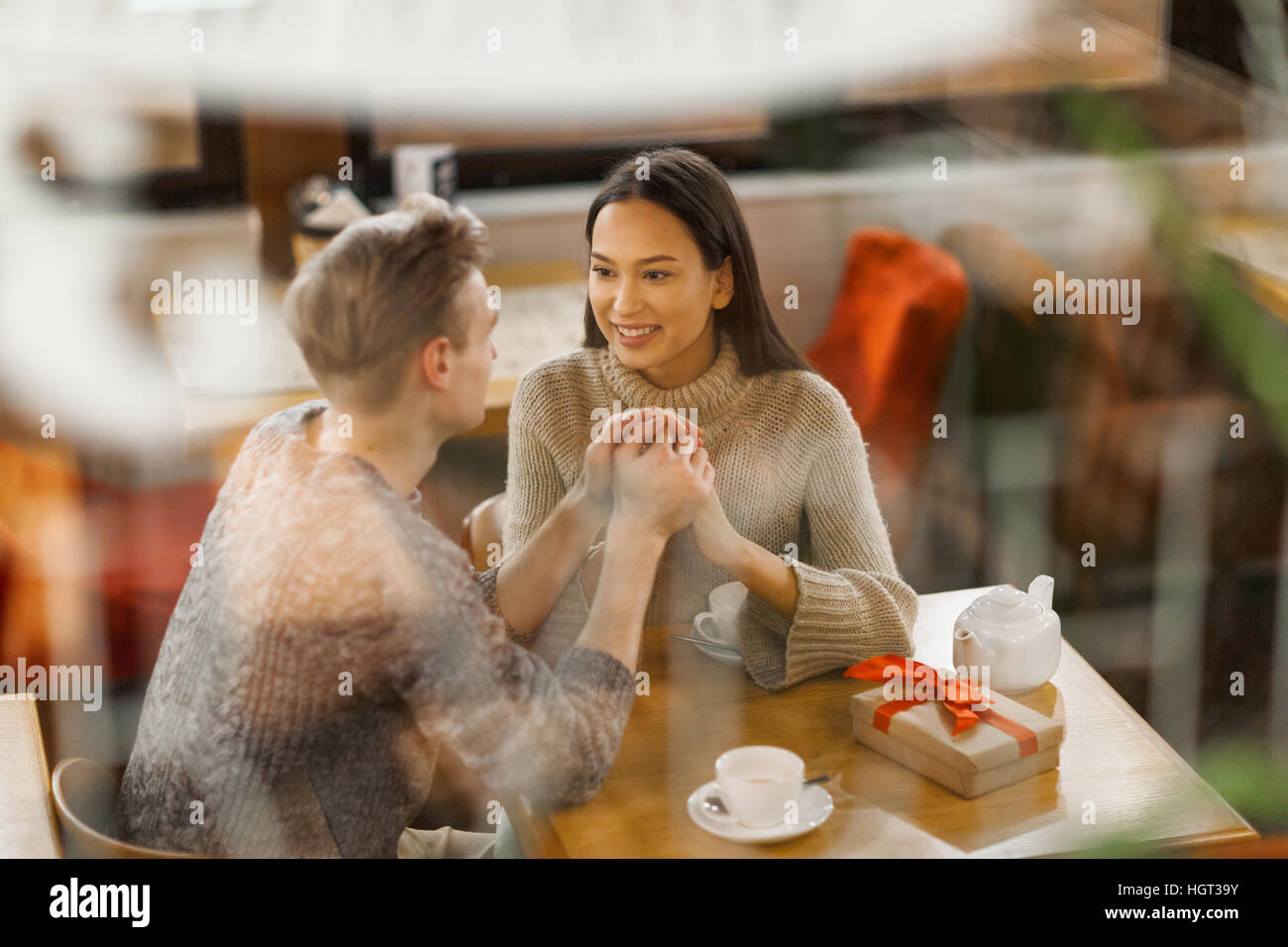 Amorous girl and guy looking at one another while sitting by table in ...