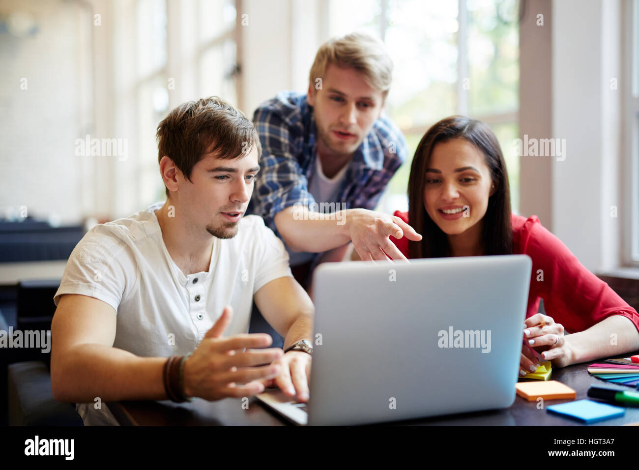Group of employees looking at laptop display at work Stock Photo - Alamy