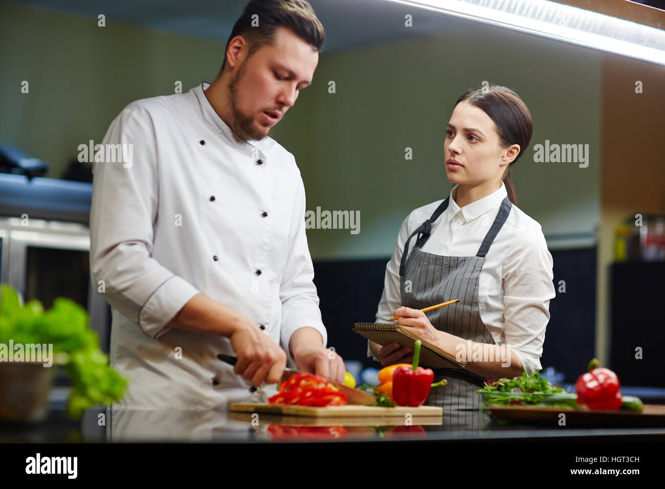 Professional chief cutting pepper and describing stages of cooking ...
