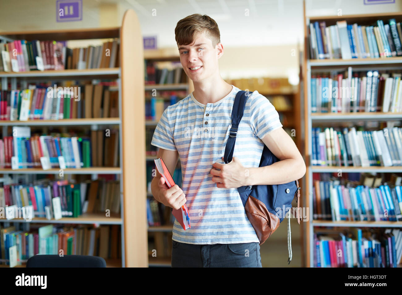 Guy with satchel looking at camera in library or classroom Stock Photo ...