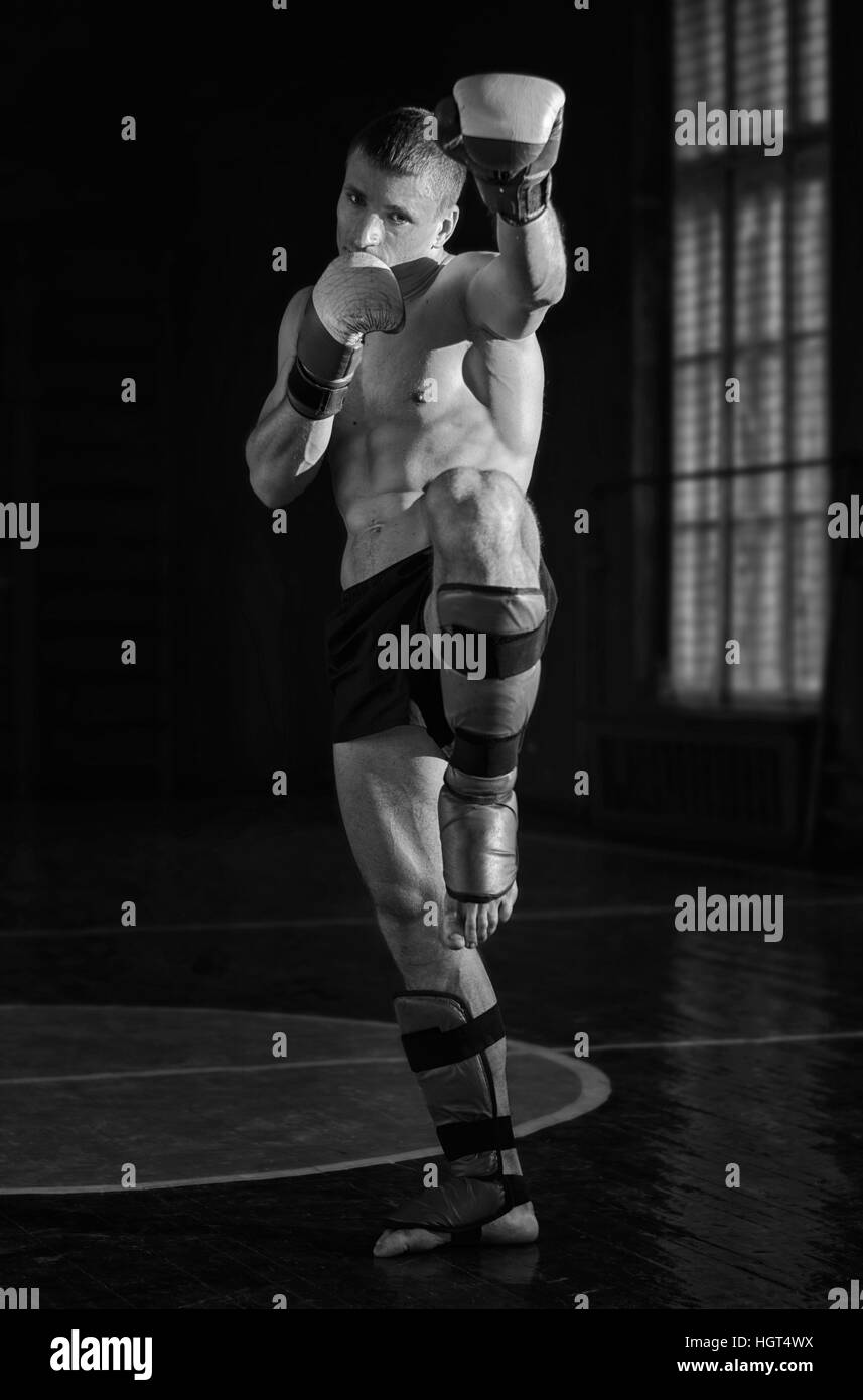 Young athletic man with boxing gloves and a rack. Black and white photo ...