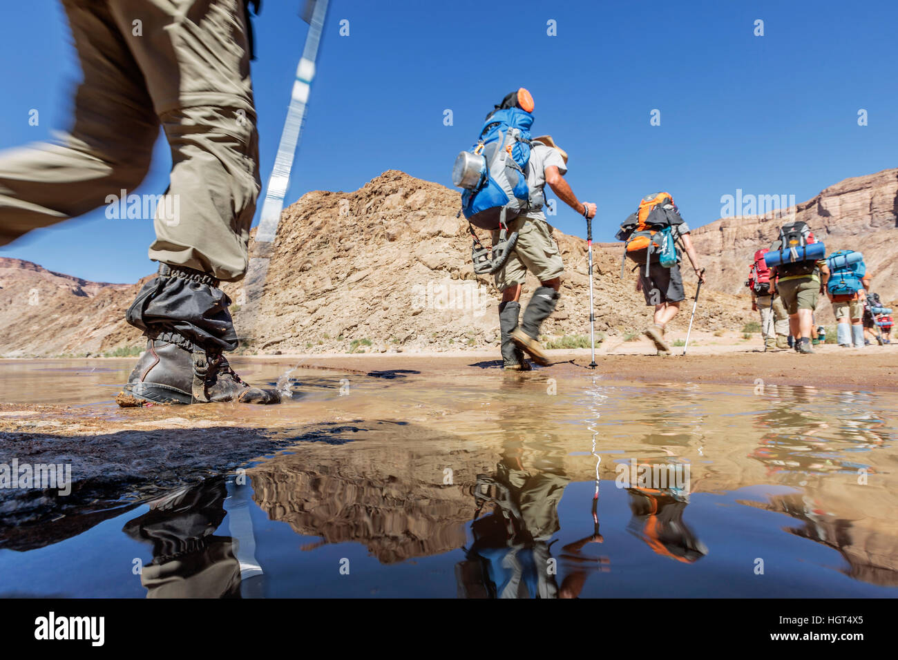 Hikers with backpacks crossing Fish River, Fish River Canyon, Namibia ...