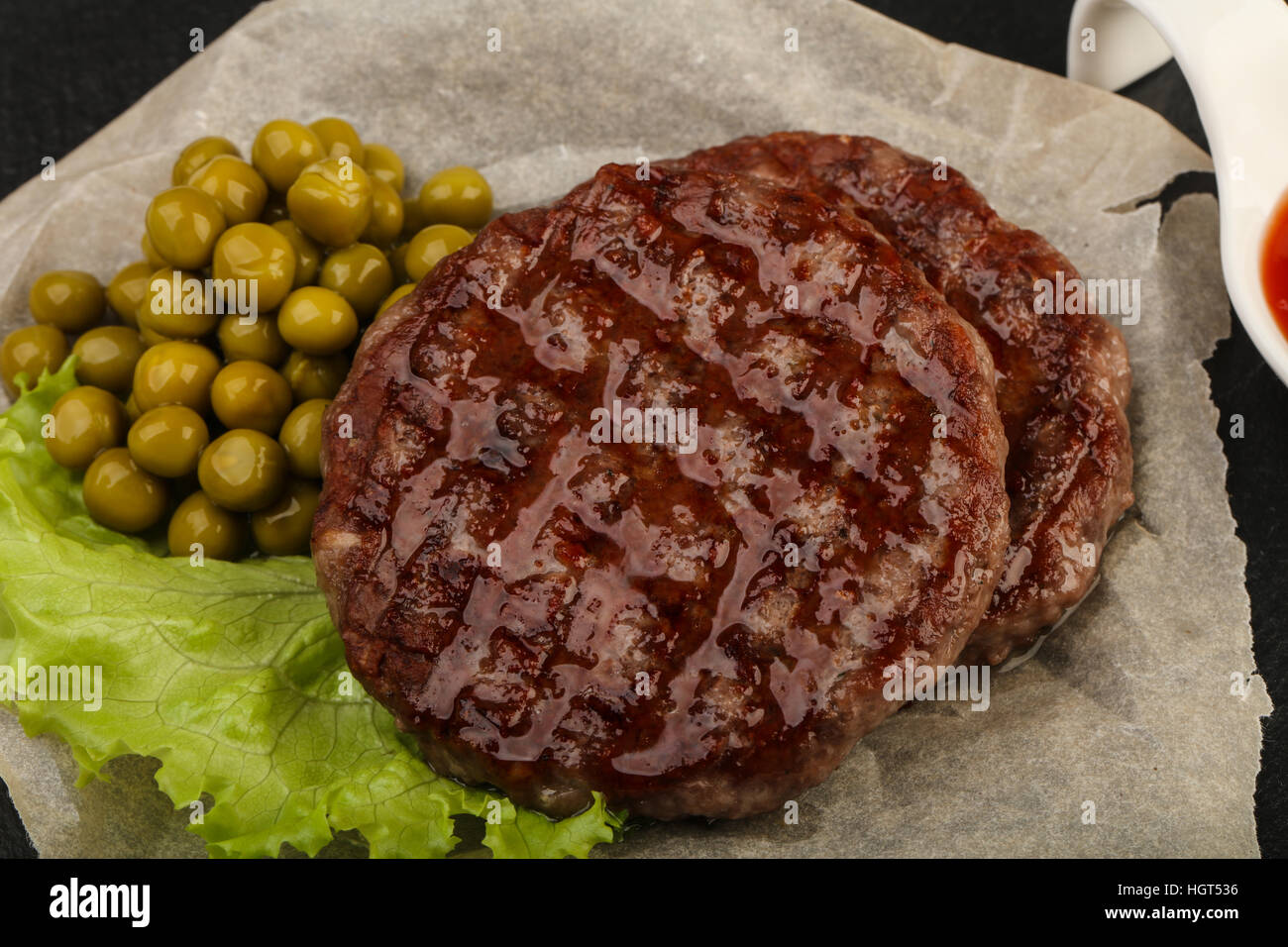 Grilled burger cutlet with peas and salad leaves Stock Photo - Alamy
