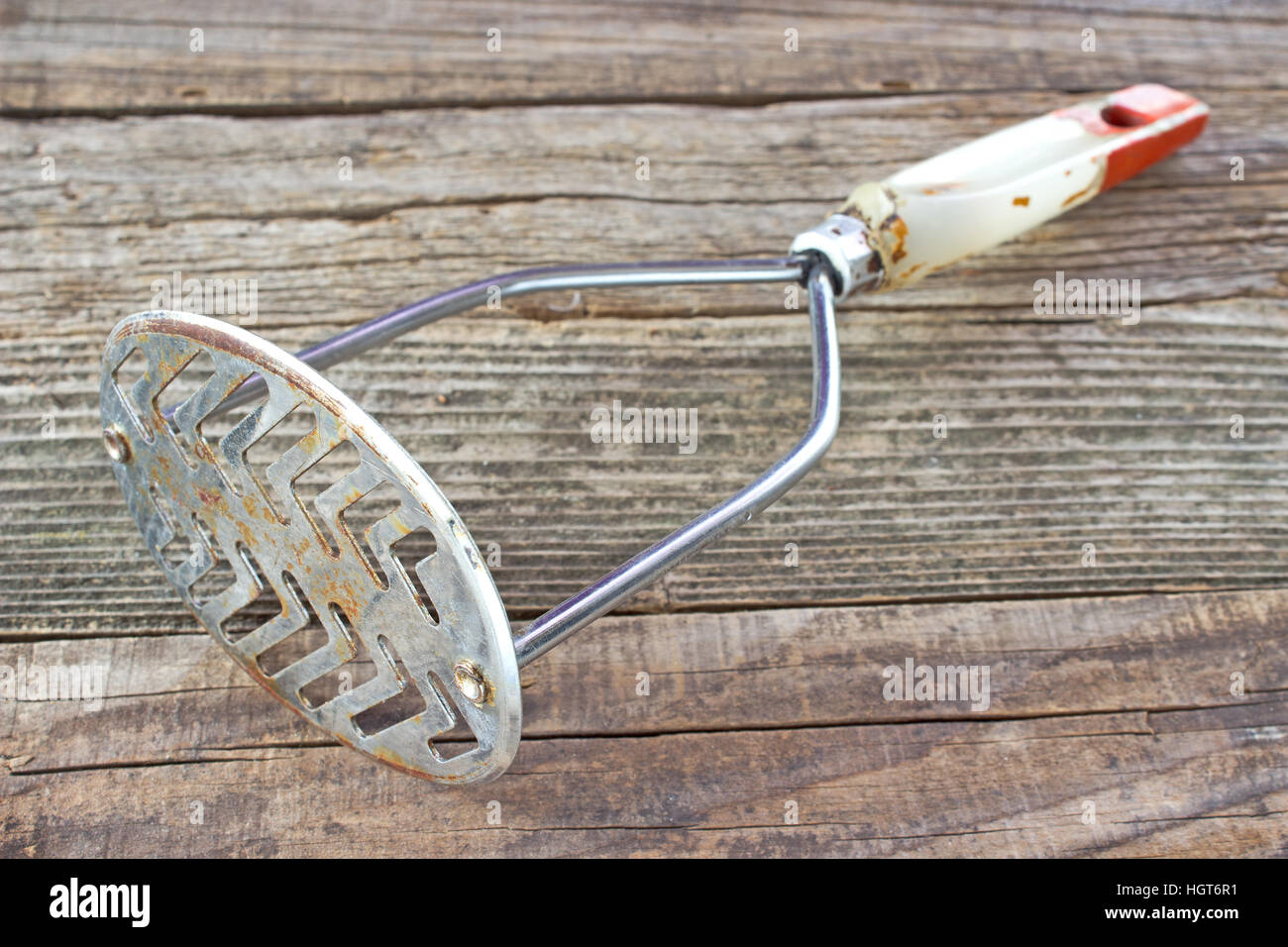 Old rusty potato masher on wooden background Stock Photo - Alamy