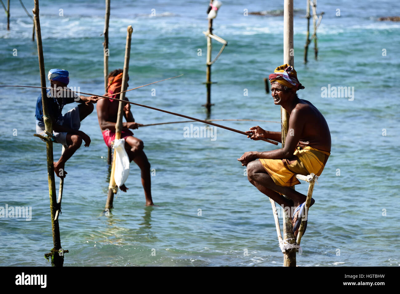 GALLE, SRI LANKA - MARCH 02:Fishermen on stilts trying to catch a fish ...