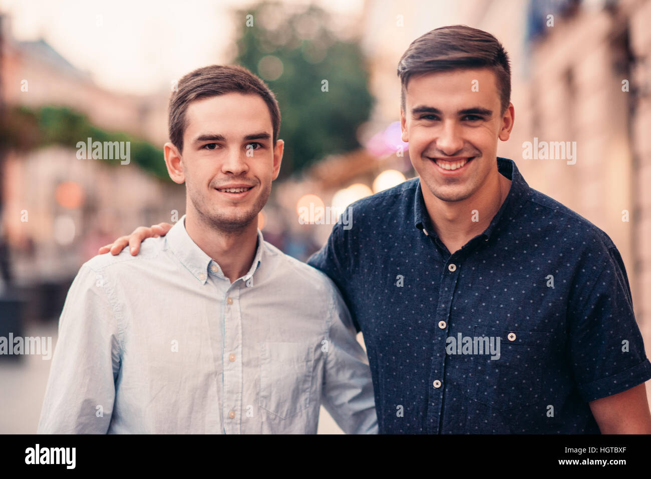 Two smiling friends standing together on a city street Stock Photo - Alamy